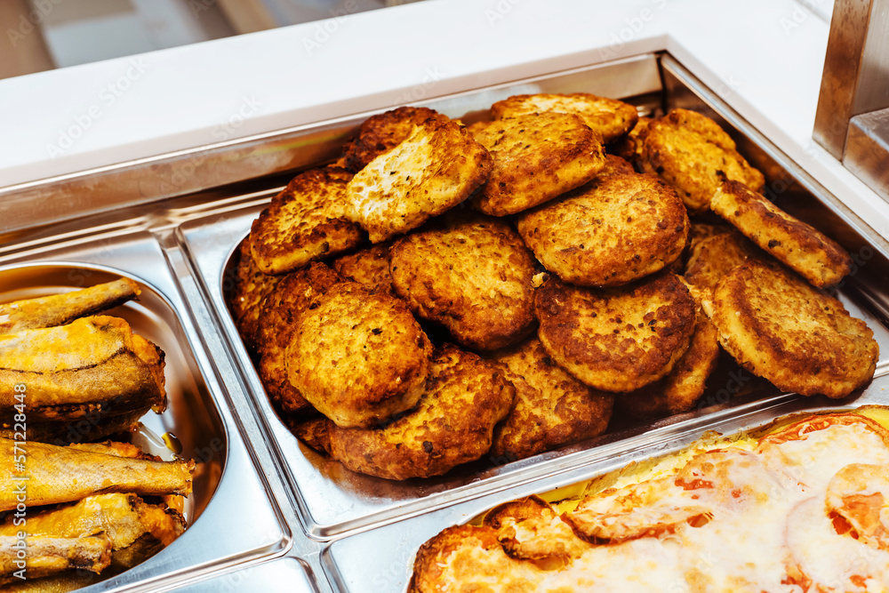 Foto de Meat cutlets on a metal baking sheet in a fast food canteen. An ...