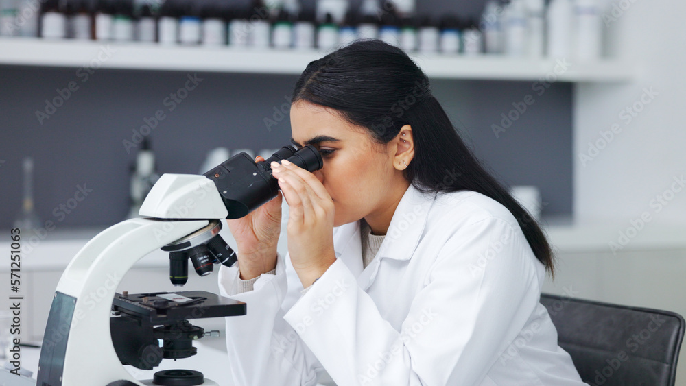 Female scientist using a microscope in a research lab. Young biologist ...