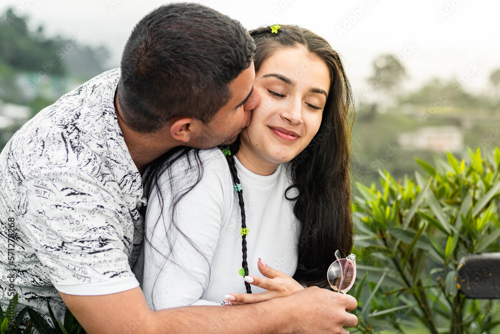 couple in love, the young man hugs her from behind while giving her a ...