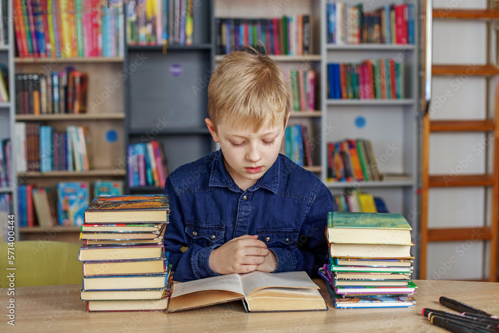 Child boy reads book from bookshelves in library. Bookstore concept ...