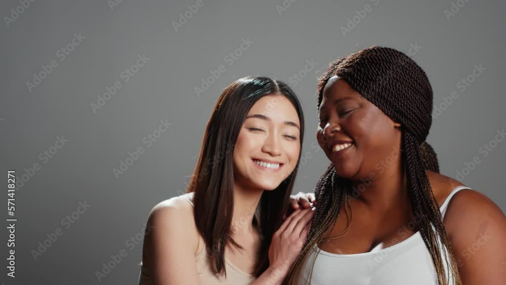 Cheerful diverse models laughing and hugging in studio, enjoying ...