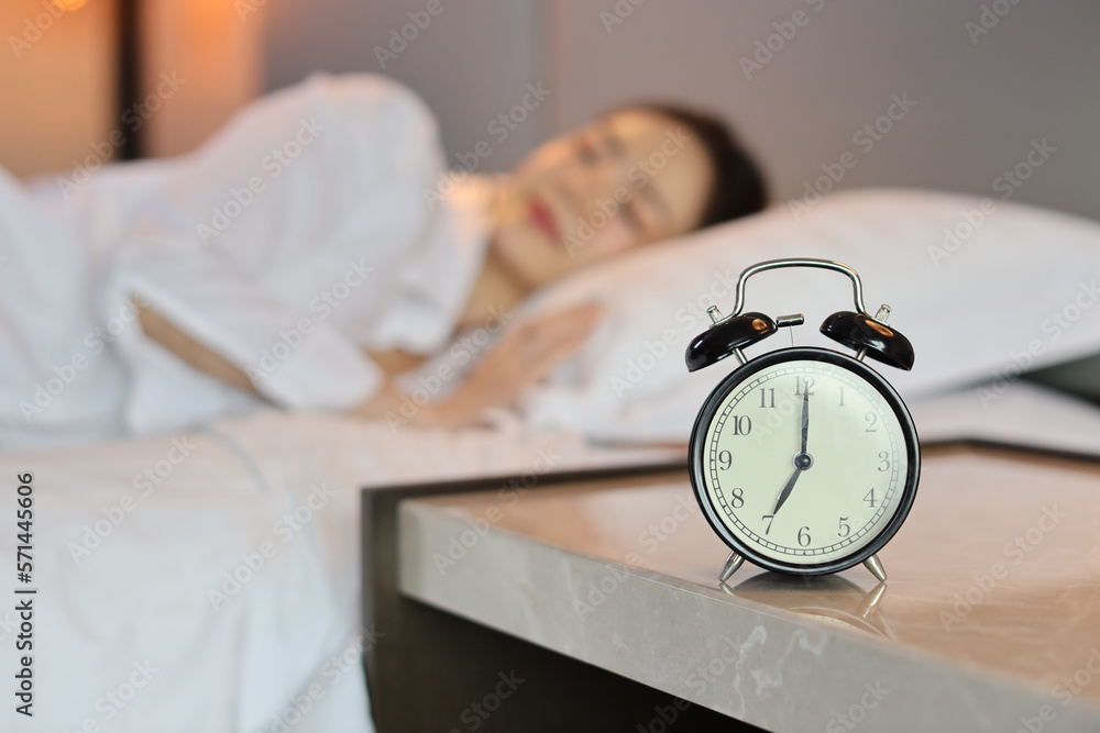 Alarm clock with blurred image of oversleeping woman wearing white ...