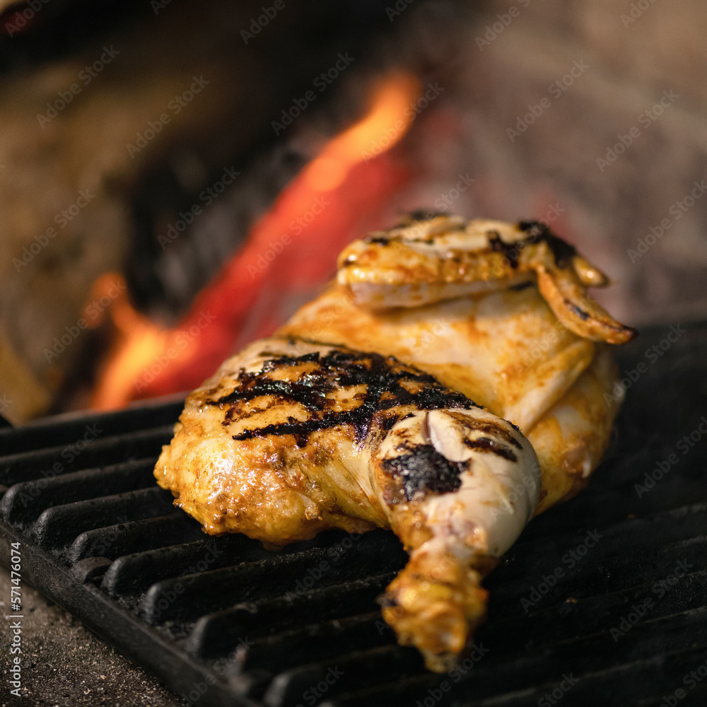 Chicken carcass fried on grill. Burning coals in background. Grill menu ...