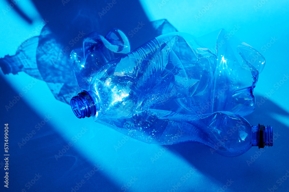 Empty deformed blue plastic bottles with a blue cap on a hay background ...