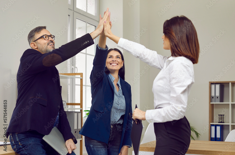 Happy successful business team giving high fives cheering their success ...