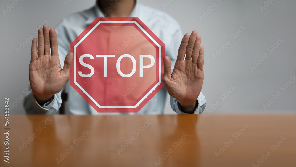 A man put hand to show symbol of stop. Stop sign is in font of palm ...