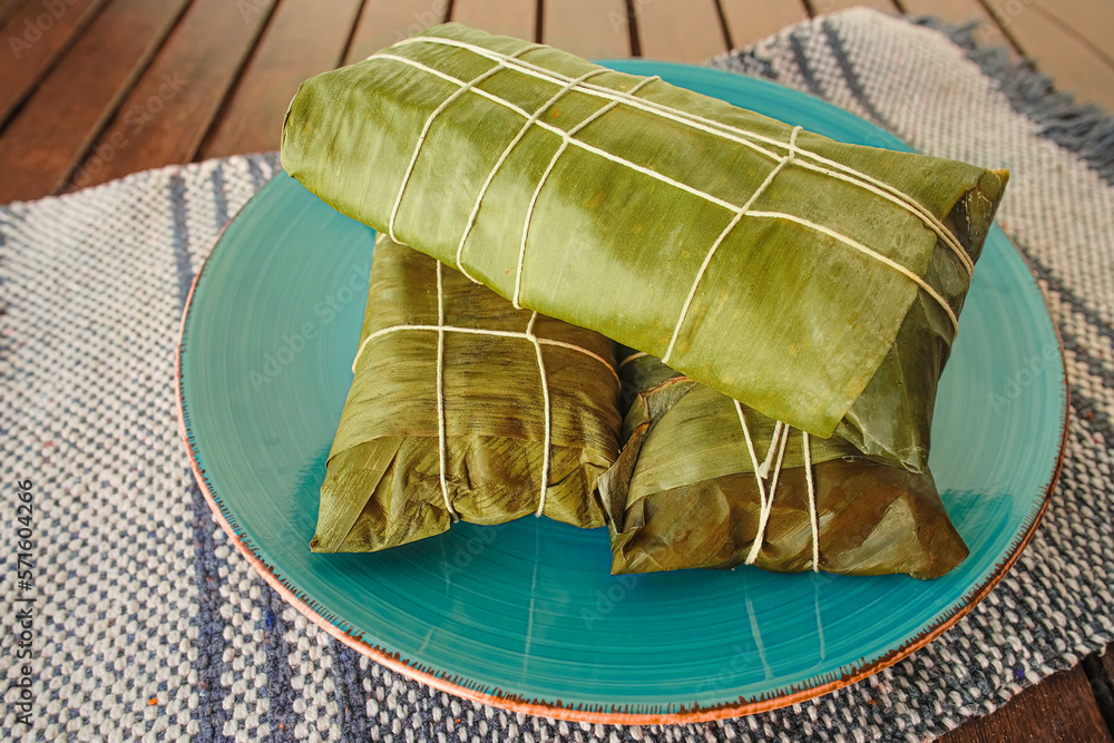 Hallaca or Tamale wrapped with plantain leaves over a rustic table and ...