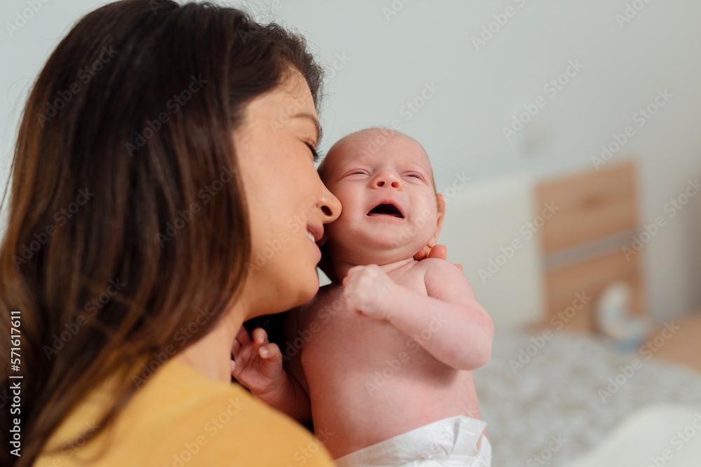 The little two-month girl cries at the mother on hands. Mother and ...