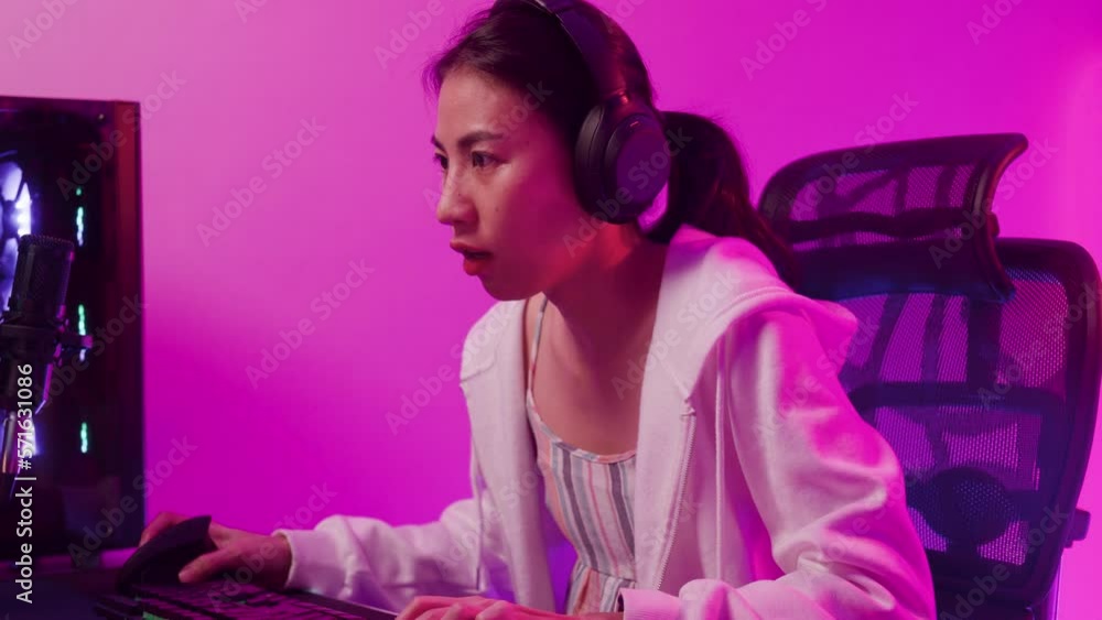 Young Asia female sit on gaming chair wear headset focus concentration ...