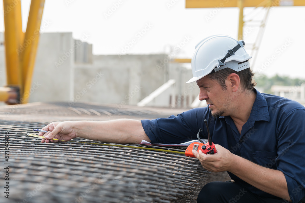 Foreman builder using tape measure inspecting construction iron lines ...