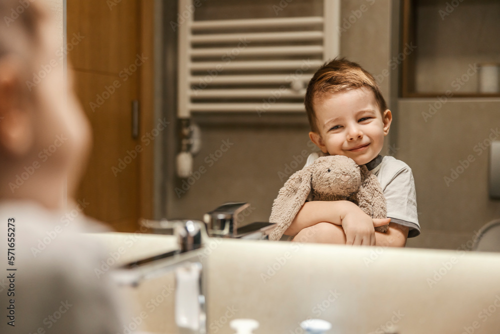 Reflection of a little boy looking himself in the mirror while hugging ...