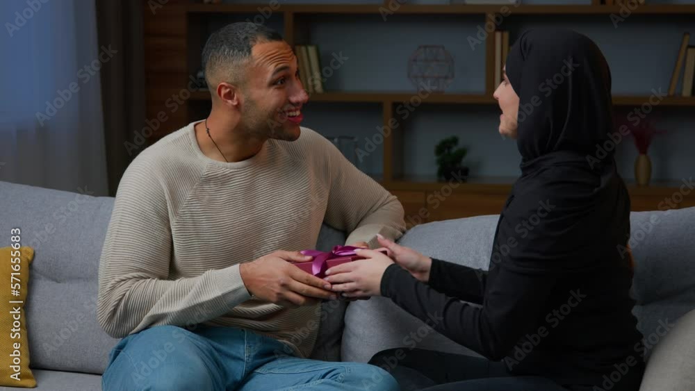 Happy husband receive gift box from loving wife Arabian muslim woman in ...