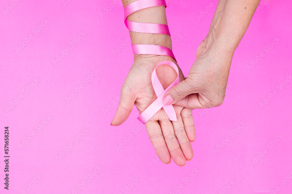 Women's hands forming the symbol of gender equality with a pink ribbon ...