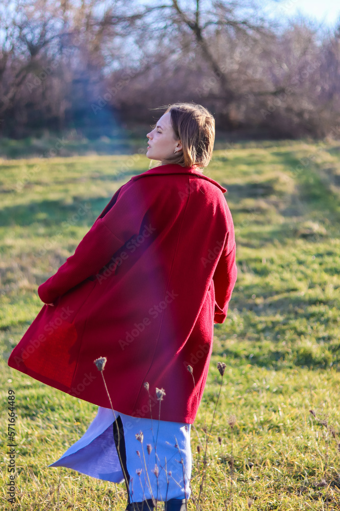 A girl in a red coat stands in nature.A woman walks.Pose in motion ...