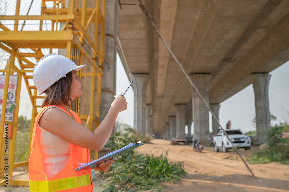 An Asian female engineer works at a motorway bridge construction site ...