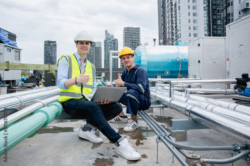 The engineer is inspecting the cooling tower air conditioner in a large industrial building to ...