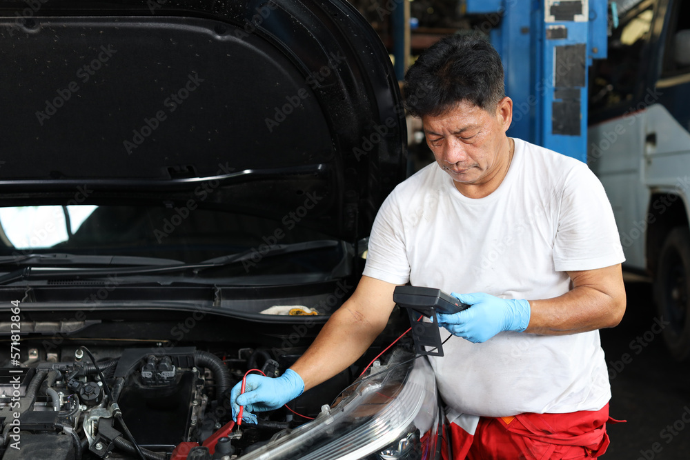 Man car mechanic in half uniform checking car battery with electricity ...