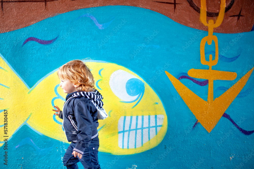 a little boy passing on the front of a street art in a gallery, Lomener ...