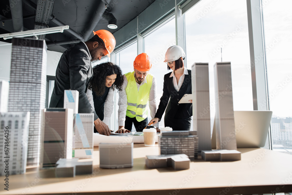 Group of four multiracial people architects standing near desk with ...