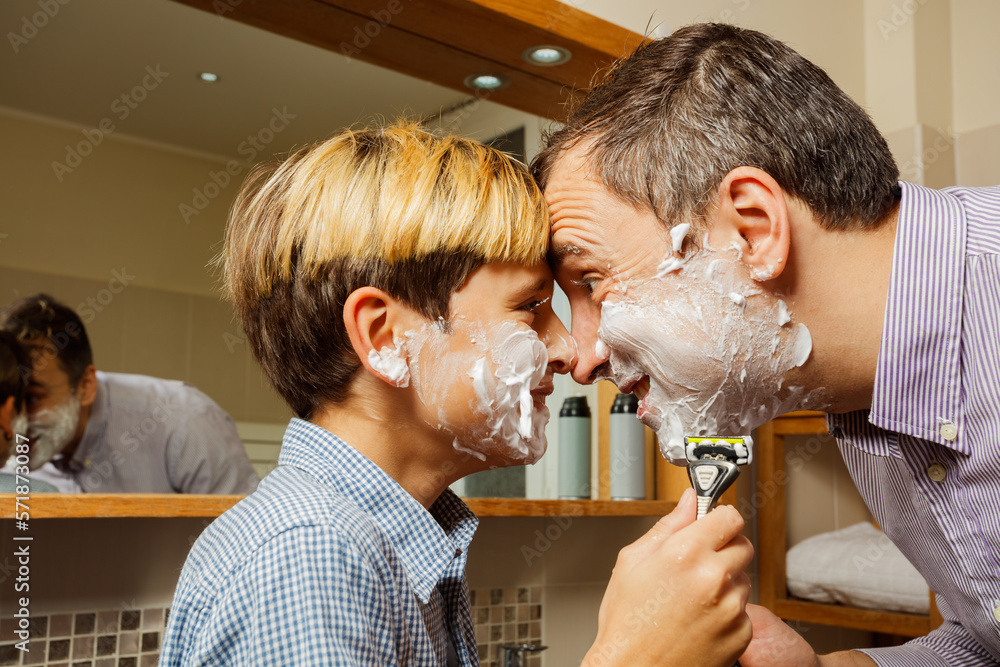 Foto de Dad with son shaving foam on face touching foreheads, laughing ...