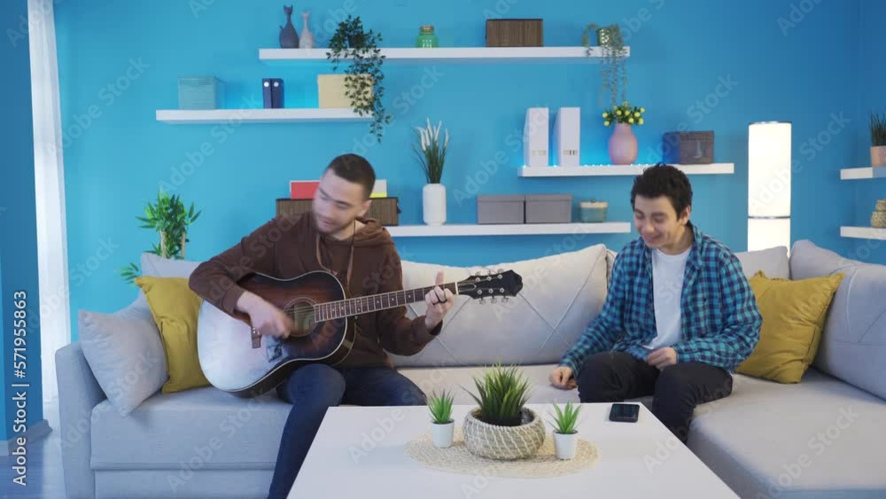 The older brother playing the guitar is singing with his younger ...