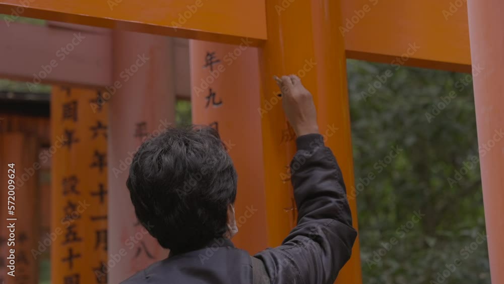 This video shows a rear view of a man repainting calligraphy on red ...