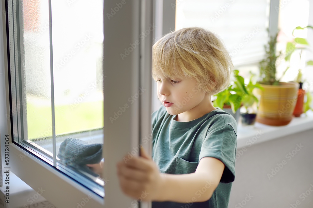 Cute little boy washing a window at home. Child helping parents with ...