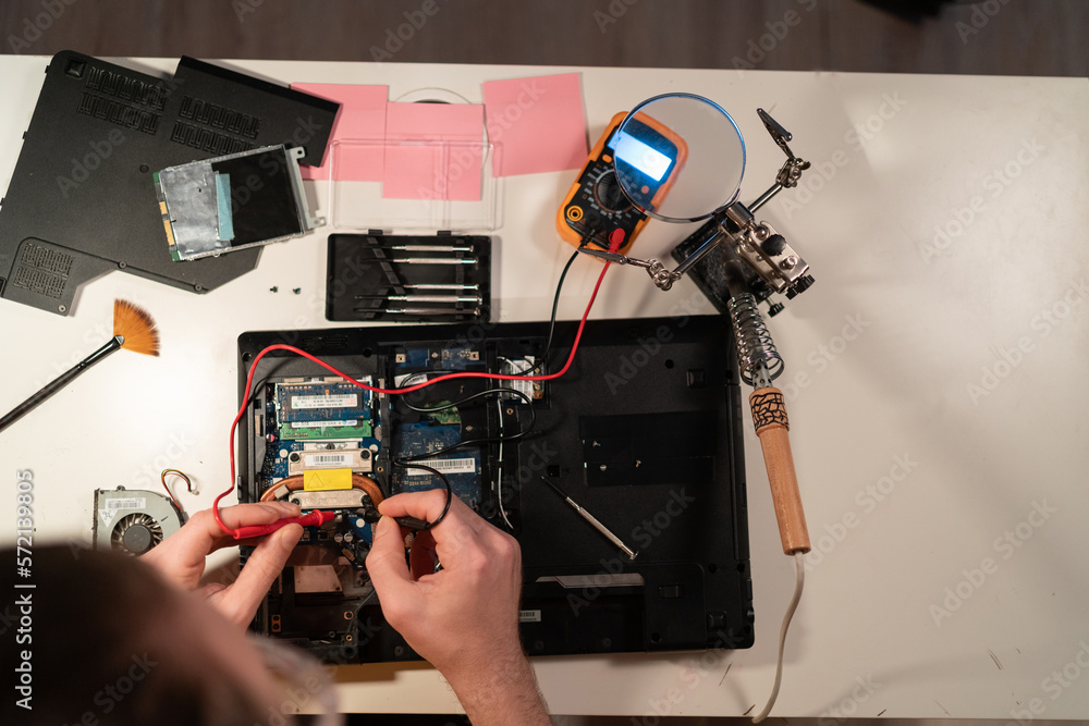 Radioman testing electric current in circuit board of disassembled ...