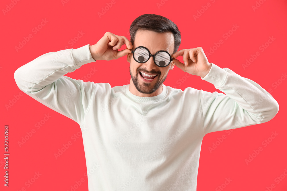 Handsome man in funny eyeglasses on red background. April Fools' Day ...