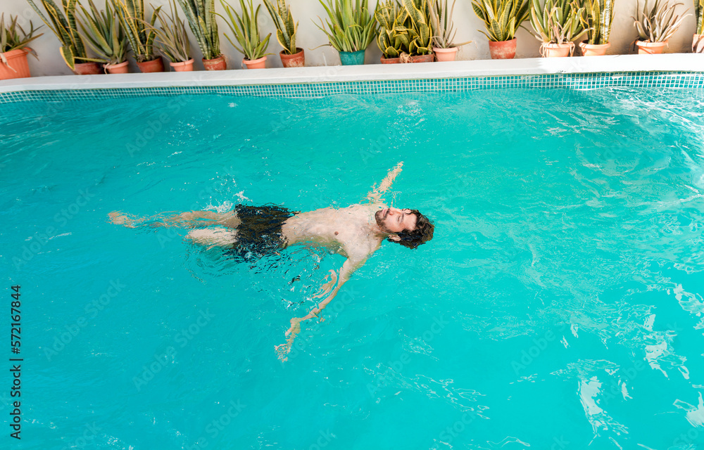 Young man swimming on his back in a hotel pool. Concept of man on ...
