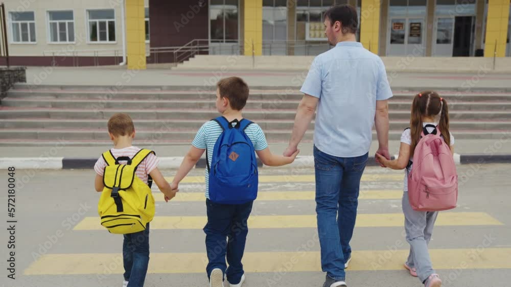 father leads child school holding his hand. dad takes children across ...