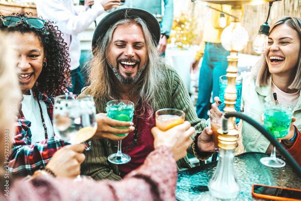 Happy friends drinking cocktails and smoking shisha in hookah lounge ...