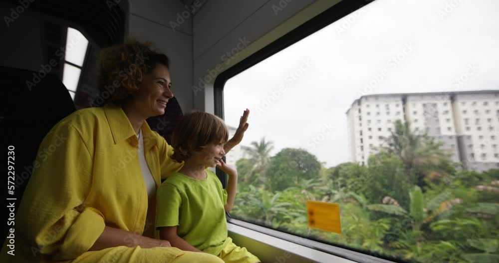 Aunt and nephew tourists in resort town smiling happily and waving to ...