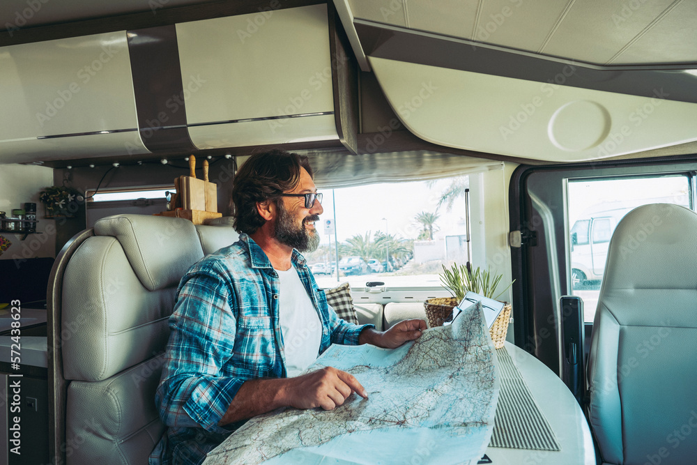 Happy mature man smilng inside a camper camping car using paper map ...