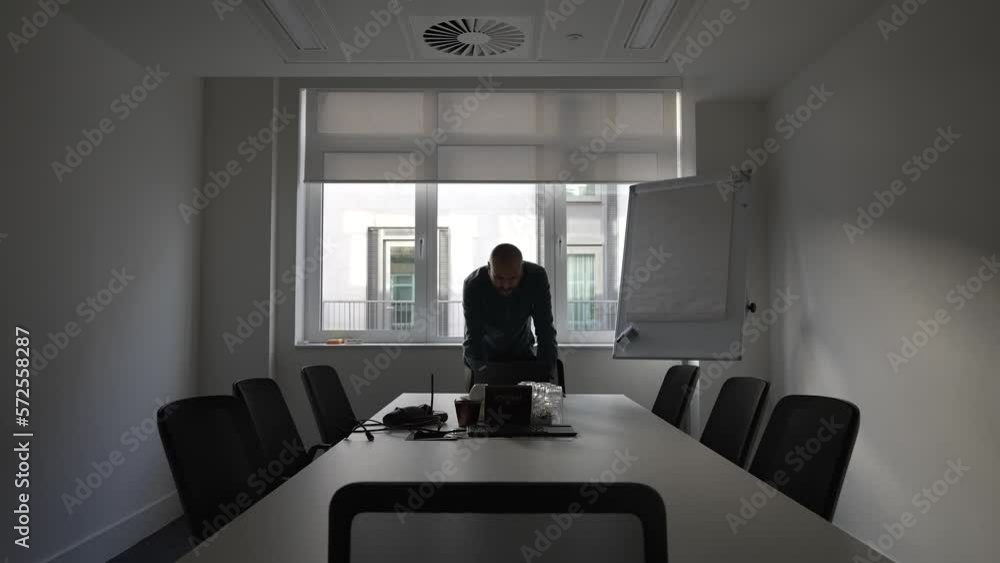 An Asian office employee standing crouched over reaching down as he ...