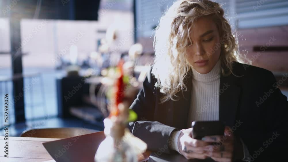 Concentrated young woman scrolling page on mobile phone while sitting ...
