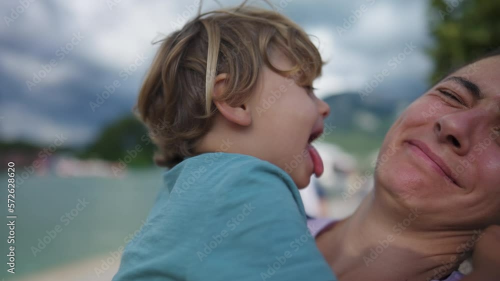 Funny cute moment of child kissing mother in cheek with tongue. Real ...