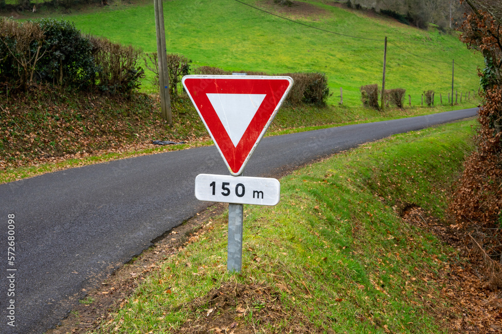 Road in countryside and give way sign. Warning triangle sign. Green ...