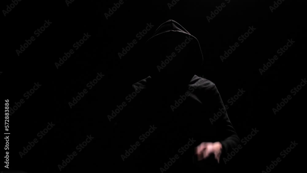 Bald man in black hoodie looks into camera before pulling up his hood ...