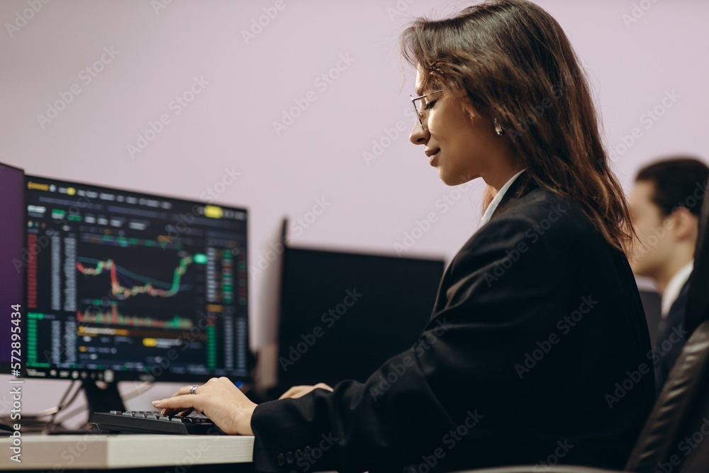 Female programmer coding in the office. Side view of a woman working as a web developer ...