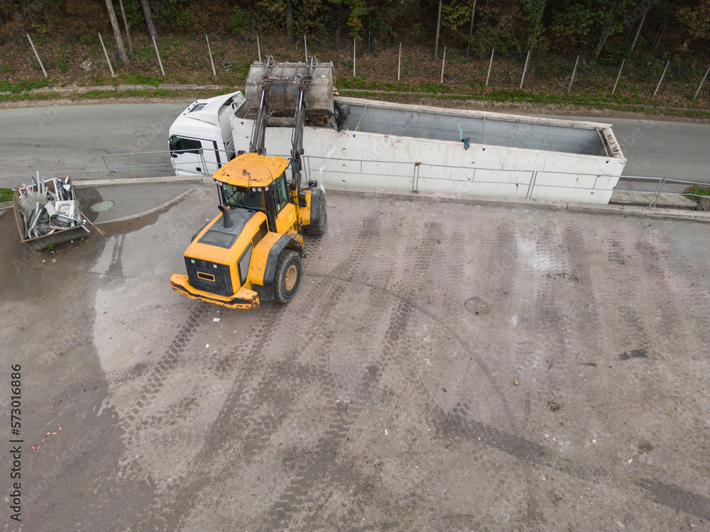 Skid steer loader loading a truck with waste material transferred for ...