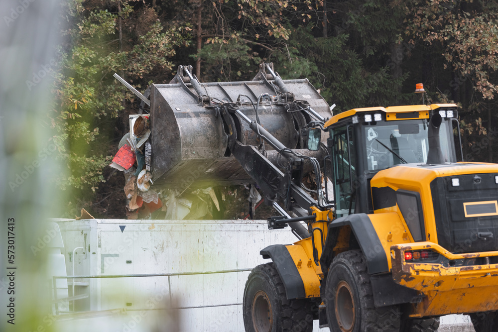 Foto de Waste loading operation, loader dumping trash in a truck on a ...