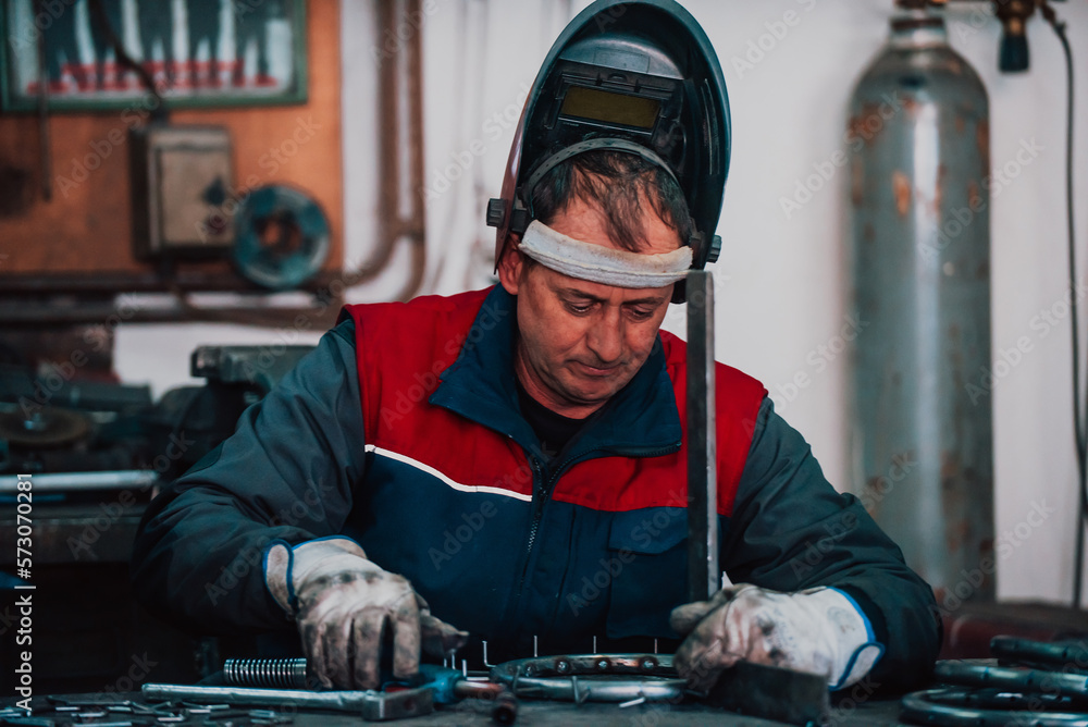 Close up welder in protective uniform and mask welding metal pipe on ...