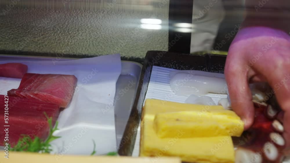 Japanese chef hand holding sushi ingredient in showcase for preparing ...