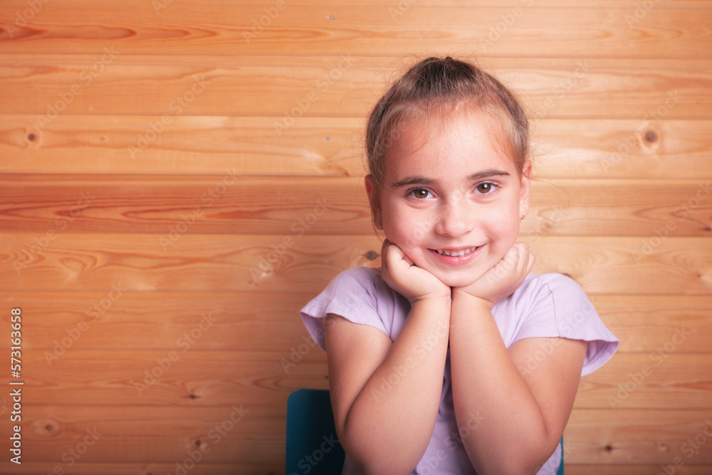 joyful shy little girl sit, propping up face with her hands. close-up ...