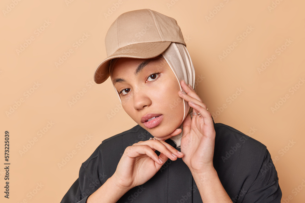 Portrait of serious Islamic woman touches face gently looks directly at ...