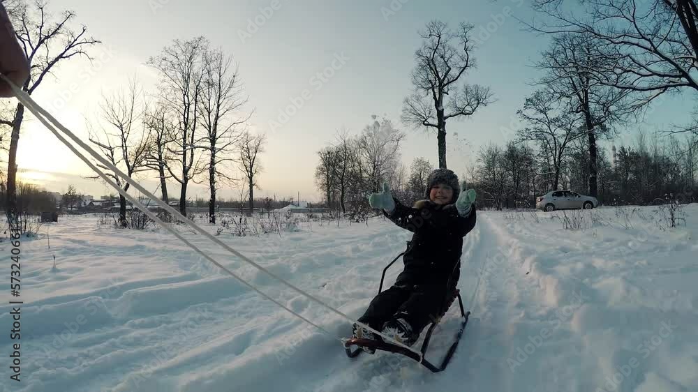 Caucasian kid funny child boy toddler rides a sled and throws fluffy ...
