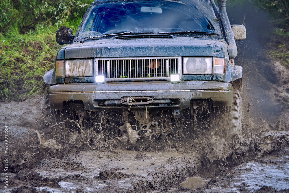 Blue SUV participating in an off road race is driving through water mud ...