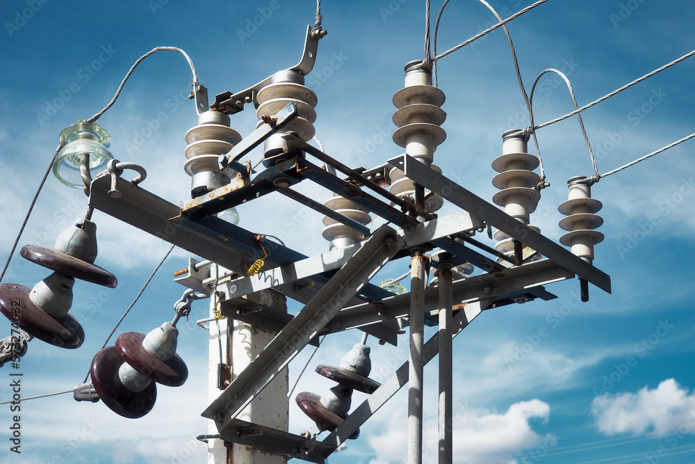High-voltage pole with insulators and wires against blue sky. Electric ...