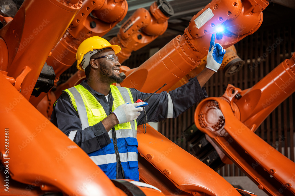 Black male engineer holding a walkie-talkie radio wearing a safety ...